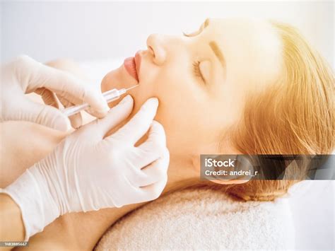 햇볕이 잘 드는 의료 센터에서 눈을 감고 미용 주사를 받는 아름다운 여성 미용사 의사는 주사기로 여성의 얼굴에 미용 시술을 하고 있다 미용 의학 및 수술 개념 20 24세에