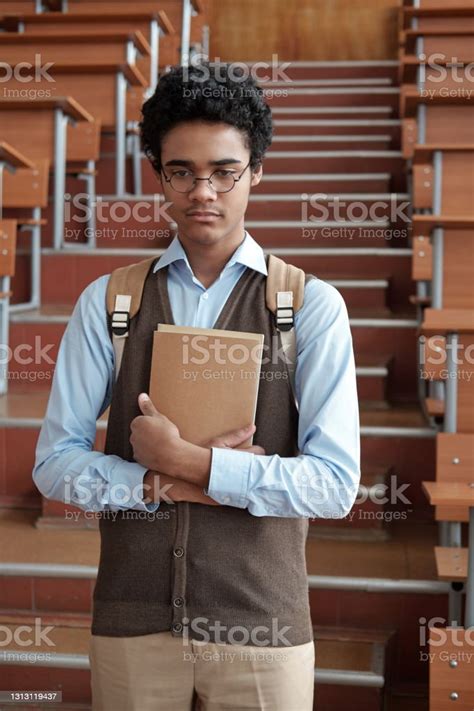 스마트 캐주얼웨어와 안경을 쓰고 책을 들고 있는 심정하거나 기분을 상하게 한 이문화 남성 학생 18 19세에 대한 스톡 사진 및 기타 이미지 Istock