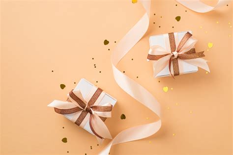 발렌타인 데이 장식 의 상단 보기 사진 빛나는 갈색과 빛 베이지 색 리본 곱슬 리본 황금 하트 모양의 색종이와 카피 스페이스와 고립 된 베이지 색 종이에 스팽글 흰색 선물