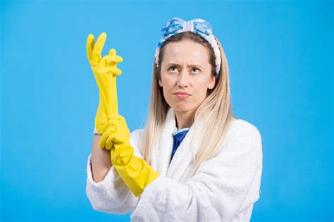청소를 위해 노란색 고무 장갑을 착용 한 아름다운 젊은 여성의 초상화 소녀는 바보 같은 긴장된 얼굴을 만들고 그녀는 깨끗한 것을