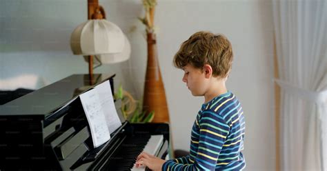 거실에서 피아노를 치는 아름다운 어린 소년 태블릿 앱으로 악기 연주를 배우는 재미를 느끼는 아이 홈스쿨링 코로나 바이러스 봉쇄 중 E 러닝 개념 사진 Unsplash