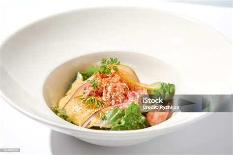 거친 그림자가있는 흰색 테이블에 게 고기 에스푸마 소스 및 양상추를 곁들인 우아한 샐러드 여름 메뉴에 게와 크림 소스를 곁들인 그린 샐러드 미적 음식 해산물 전채 갈고리