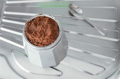 식기 세척기 위에 커피 포트를 열고 갓 빻은 스페셜티 커피로 완전히 채워집니다 갓 양조 한 향기로 갓 빻은 커피 원두로 채워진 금속 커피 필터 개수대에 대한 스톡 사진 및