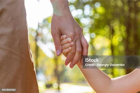 화려한 드레스 지주에 아주 작은 금발 긴 머리 아이 여자의 근접 촬영 Trustingly 배경 흐리게 화려한 화창한 여름에 야외에서 젊은 어머니의 손 가족에 대한 스톡 사진