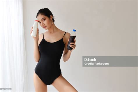 다이어트 또는 좋은 건강 개념 건강하고 스포티 한 아시아 젊은 여성이 검은 운동복을 입고있다 우유와 청량 음료 한 병을 들고있는 매력적인 소녀 그녀는 건강하거나 건강에
