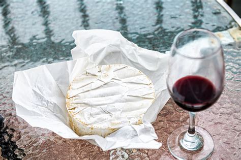 프랑스 브리 치즈 전체 라운드 휠 트럭 종이 포장 유제품 더블 크림 제품 부엌 테이블에 유리에 레드 와인 매크로 근접 촬영 붉은 포도주에 대한 스톡 사진 및 기타 이미지