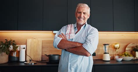 팔짱을 끼고 행복하고 저녁 식사 음식 또는 식사를 요리하기 위해 집의 부엌에서 노인의 초상화 은퇴 미소 및 웰빙다이어트 건강 또는 영양을 위해 아파트에서 자신감 있는 노인과