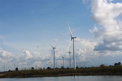 저수지에 대항하는 풍력 터빈 녹색 환경을 가진 녹색 에너지 풍력 터빈은 저수지의 지역 풍경에 농장을 두고 구름을 배경으로 푸른 하늘을 배경으로 한 전망 전력 생태 개념을