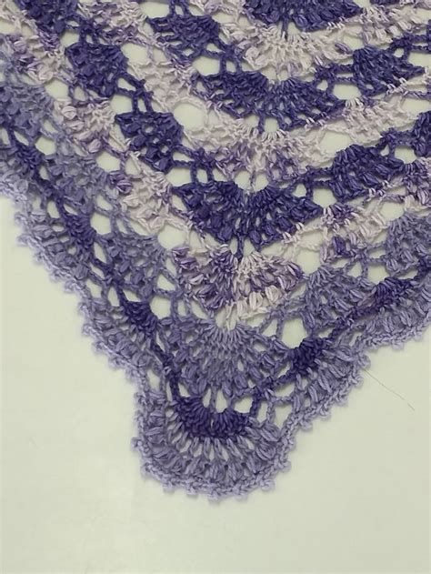 A Purple And White Crocheted Shawl On A Table