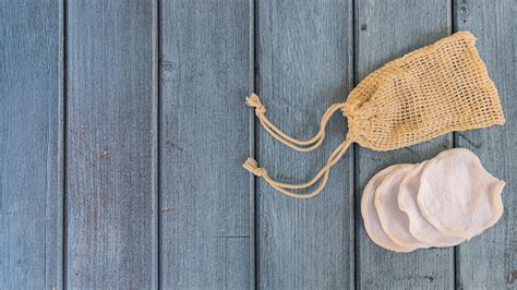 천연 코튼 재사용 가능한 메이크업 리무버 패드는 파란색 나무 배경에 에코 백으로 제공됩니다 플랫 레이 복사 공간 플라스틱 무료