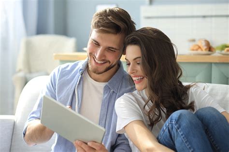 거실의 소파에 앉아 태블릿에서 온라인 미디어 콘텐츠를보고 젊은 부부 구매에 대한 스톡 사진 및 기타 이미지 구매 벨라루스 보기 정적 활동 Istock