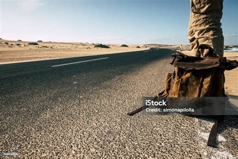 가죽 배낭 여행과 남자의 관점을 가까이 하 고 함께 여행을 공유 하는 자동차를 기다릴모래와 사막 모래 언덕과 검은 아스팔트도로는 라이프 스타일을 즐기는 여행자를 위한 가죽에