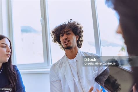 한 젊은 아프리카계 미국인 의사는 스마트 태블릿을 사용하여 현대 병원의 동료 의사들에게 자신의 업무 및 환자 치료 계획을 자신 있게 제시하여 협업과 고급 의료 관리를