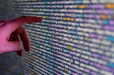 A Close Up Image Of A Hand Pointing At A Code Display On A Large Screen