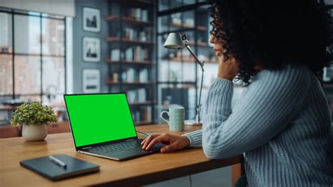 테이블에 앉아있는 동안 홈 거실에서 녹색 화면 모의 디스플레이와 노트북에서 작업 여성 전문가를 닫습니다 소셜 네트워크에서