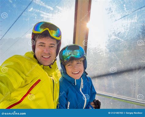 Smiling Skiers Dad And His Teen Son On Sunny Cable Car Lift Ride Stock