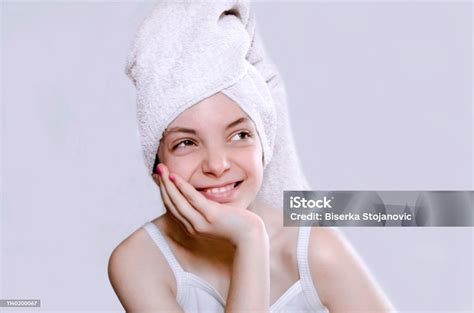머리에 수건을 가진 사춘기 소녀는 손에 머리를 기대어 미소 회색 배경에 고립 된 행복 한 어린 소녀의 초상화 건강관리와 의술에
