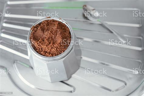 식기 세척기 위에 커피 포트를 열고 갓 빻은 스페셜티 커피로 완전히 채워집니다 갓 양조 한 향기로 갓 빻은 커피 원두로 채워진 금속 커피 필터 개수대에 대한 스톡 사진 및