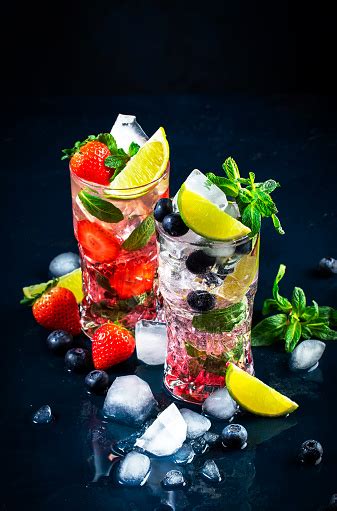 추운 여름 딸기와 블루베리 모히토 칵테일 음료는 라임 화이트 럼 소다 사탕수수 설탕 민트 얼음을 짙은 파란색 배경에 하이볼 잔에 담았다 시원하고 상쾌한 음료 Gin