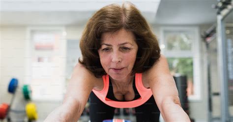 피트니스 훈련의 일환으로 바닥에 복근을 위해 휠 롤러로 운동하는 체육관에서 스포츠 의류를 입은 아름다운 노인 여성 사진