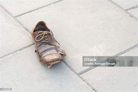 단 하나의 고독한 손상된 찢어진 신발은 보도에 남아 있으며 물체 클로즈업 아무도 없습니다 돈 빈곤 노숙자 단순한 추상적 인 개념 사람이 없습니다 바닥에 버려진 오래된 신발
