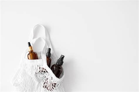 세럼 오일 산 로션은 갈색 드롭퍼 유리에 파이펫이 있는 흰색에 평평하게 놓여 있습니다 스파 제품 친환경 재사용 가능한 쇼핑백