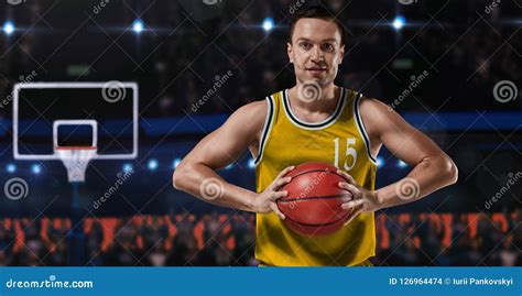 Баскетболист в желтой форме стоя на баскетбольной площадке Стоковое Фото изображение