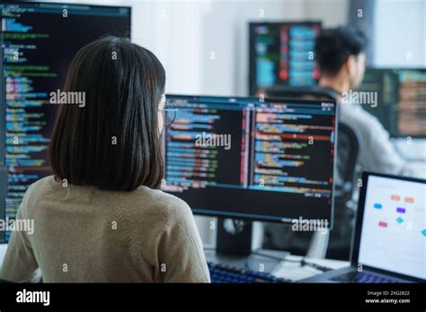 Asian Software Developers Working On Multiple Screens Displaying Code