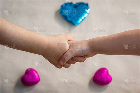 儿童握手米色背景与红色和蓝色的心