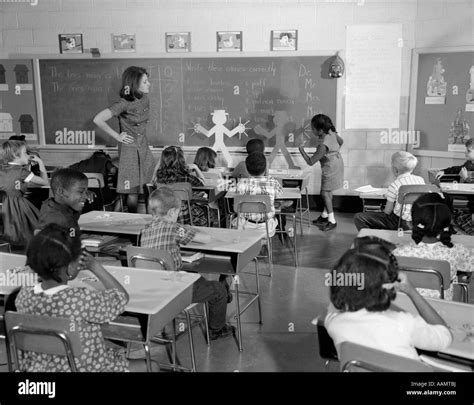1960s Back View Of Grade School Classroom With Teacher At Front Stock