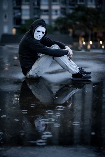 버려진된 건물의 옥상에서 비에 앉아 그의 무릎을 껴 안고 하얀 마스크에 미스 테리 까마귀 남자의 반사 양극성 장애 또는 주요 우울증 장애입니다 우울증 개념 가린 얼굴에 대한