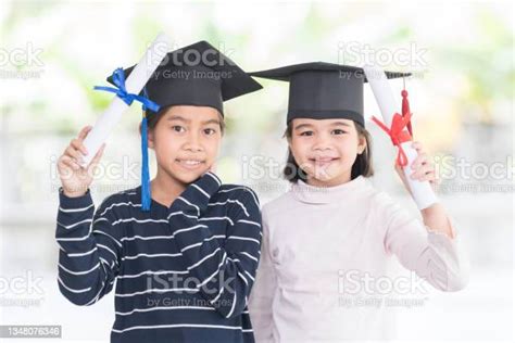 졸업 모자를 가진 두 개의 행복한 아시아 여성 학교 아이 졸업생은 압연 인증서를 보유하고 2명에 대한 스톡 사진 및 기타 이미지