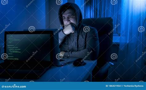Thoughtful Programmer In Hood Looking On Laptop Screen While Working At