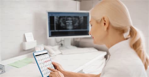 이달의 계획 웃는 치과 의사는 태블릿을 손에 들고 사무실에 앉아 달력에서 그녀의 계획을 보고 있습니다 사진 Unsplash의 건강한 라이프 스타일 이미지