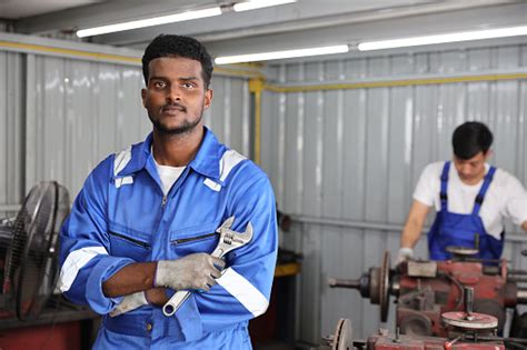 기술자 정비사는 렌치로 팔짱을 끼고 금속 선반 기계에서 작업하는 동안 차고에서 자동차 디스크 브레이크 연마를 작동합니다 유지 보수 자동차 및 검사 차량 부품 개념 기술자에