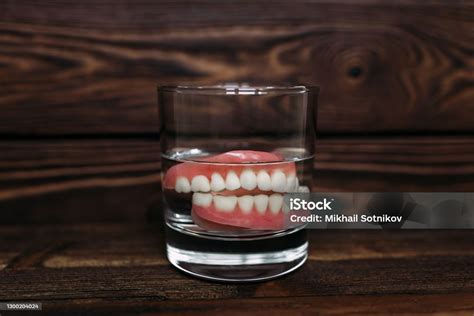 물 한 잔의 틀니 치과 보철 관리 턱의 전체 이동식 플라스틱 틀니 두 개의 아크릴 의치 가짜 이빨이있는 위쪽과 아래턱 틀니 또는