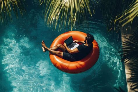 Man Working Remotely On A Laptop While Floating In A Pool On An Orange