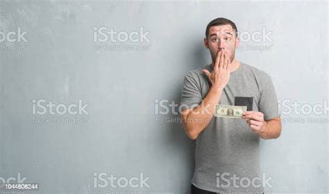 1 달러 커버 입을 손으로 보여주는 회색 그런 지 벽에 젊은 백인 남자는 실수 두려움 침묵 비밀 개념에에서 무서 워의 표현에 대 한 수치와 충격 가리기에 대한 스톡 사진 및