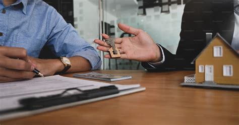 부동산 중개인의 자른 이미지는 현대적인 나무 테이블에서 파란색 셔츠를 입은 똑똑한 남자에게 주택 보험 또는 주택 소유권을 제공합니다 계약에 서명 브로커판매자딜러 개념