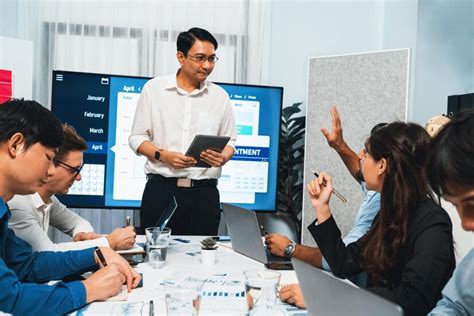 프로젝트 관리자는 프로젝트 관리 소프트웨어 디스플레이를 사용하여 팀과 의사소통하고 협업하여 프로젝트 작업의 진행 상황을 모니터링하고 회의 테이블에서 일정 계획을 세 ⁇ 니다