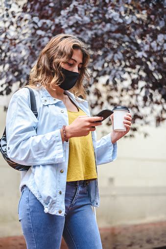 거리에서 마스크를 쓰고 커피 한 잔을 마시고 전화를 사용하는 젊은 빨간 머리의 여성 2020년에 대한 스톡 사진 및 기타 이미지 2020년 25 29세 Brand