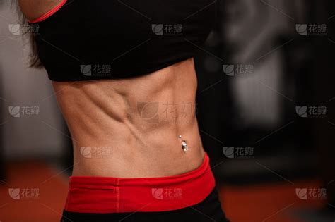 运动女孩在健身房展示腹肌，女人在紧张