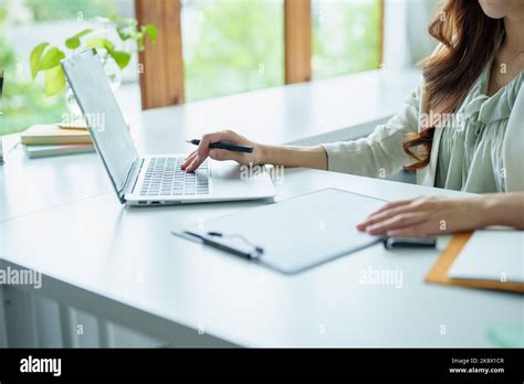 Portrait Of An Asian Bank Employee Using A Computer And Documents To
