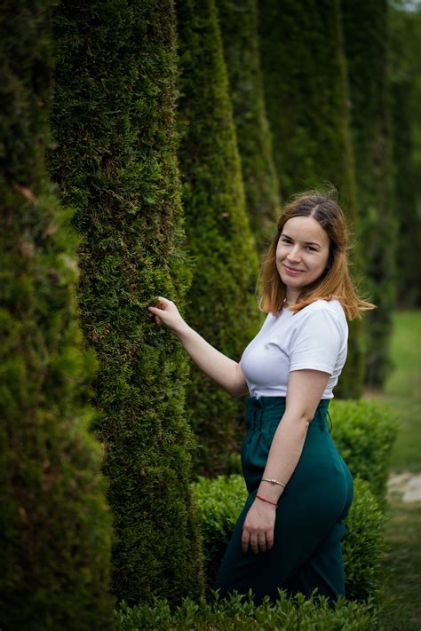 A Woman Standing Between Two Tall Green Trees Photo Free Romania Image On Unsplash