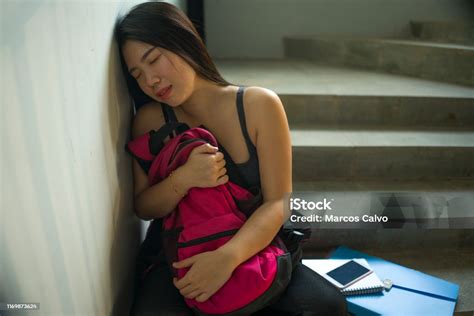 아시아 여자 대학생 괴롭힘의 극적인 초상화 캠퍼스 계단에 외로운 앉아 있는 젊은 우울하고 슬픈 한국 소녀는 괴롭힘과 괴롭힘을 겪고 절망적이고 배제되었습니다 계단에 대한 스톡