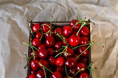 자른 나무 상자 꼬리와 잎이 있는 달콤한 빨간 체리의 크레이프가 노란색 주름진 종이 배경에 있습니다 여름 과일과 열매 수확 및 작물 개념 유기농 식품 위쪽 보기 0명에 대한