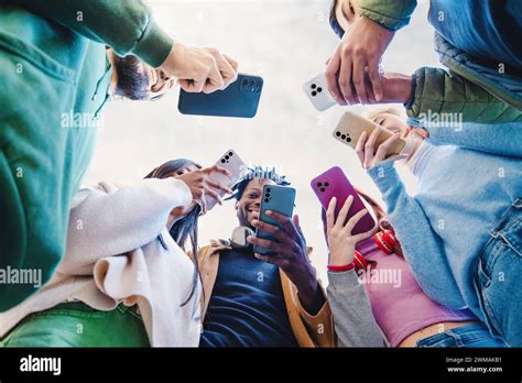 Group Of Young Adults Engaged With Their Smartphones Sharing Content