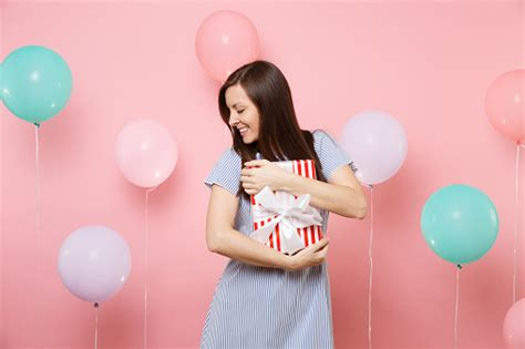 블루 드레스를 포옹 선물 다채로운 공기 풍선 파스텔 핑크 배경에 빨간색 상자가 부드러운 매력적인 여자의 초상화 생일 휴가 파티 사람들이 진심으 감정 14에 대한 스톡 사진