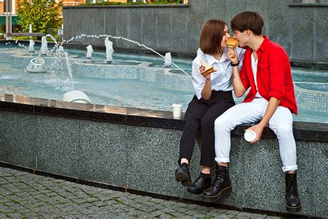 함께 야외에서 점심을 먹는 남자와 여자 햄버거와 샌드위치를 먹는 커플 패스트 푸드와 길거리 음식의 개념 18 19세에 대한 스톡