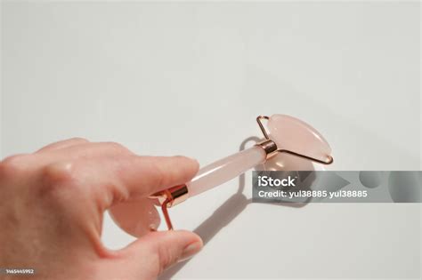 괄사 롤러는 밝은 배경에 여성 손에 석영으로 만들었습니다아름다움 장치 구아 샤 얼굴 마사지 장치 핑크 천연석으로 만든 롤러 마사지기 괄사에 대한 스톡 사진 및 기타 이미지